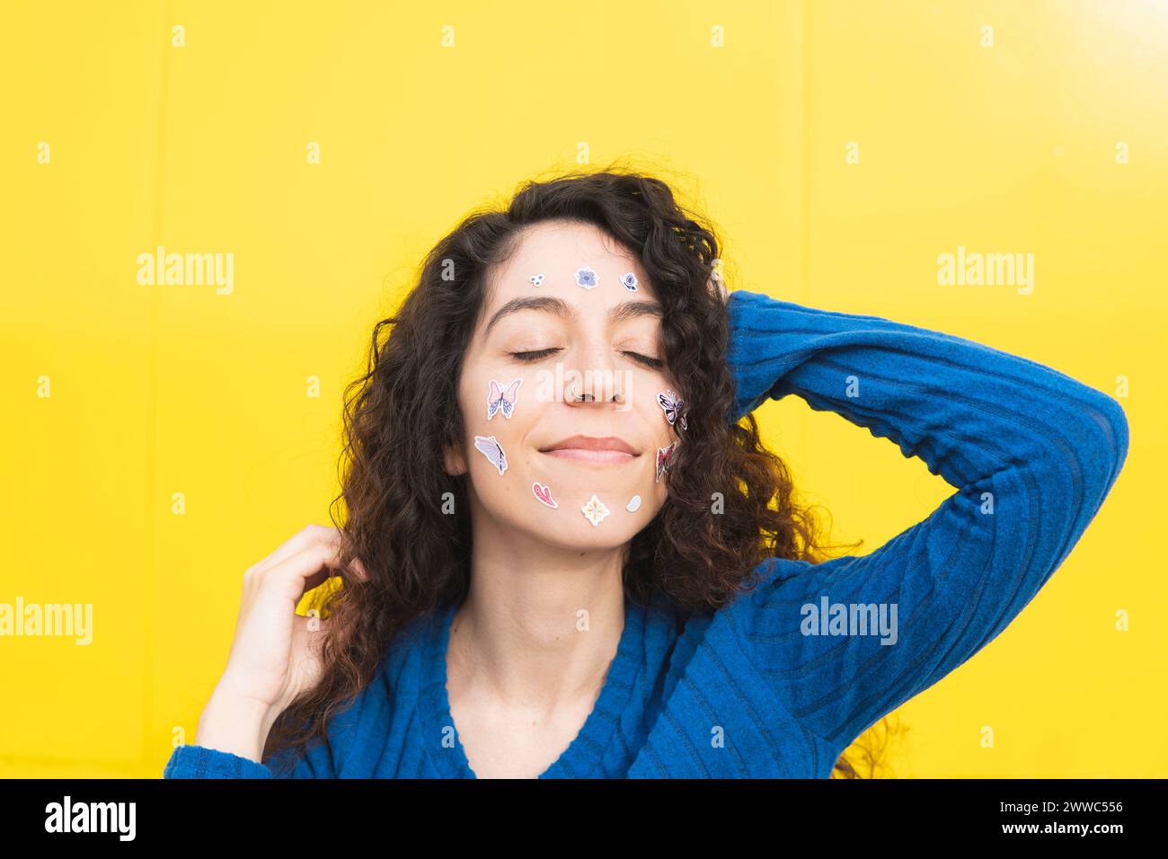 Woman with various stickers on face against yellow background Stock ...