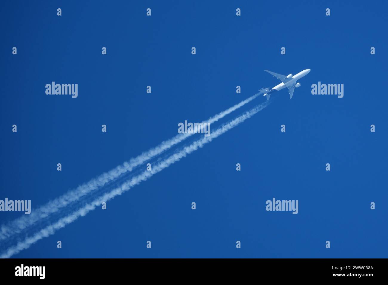 Airplane in the blue sky with contrail Stock Photo - Alamy