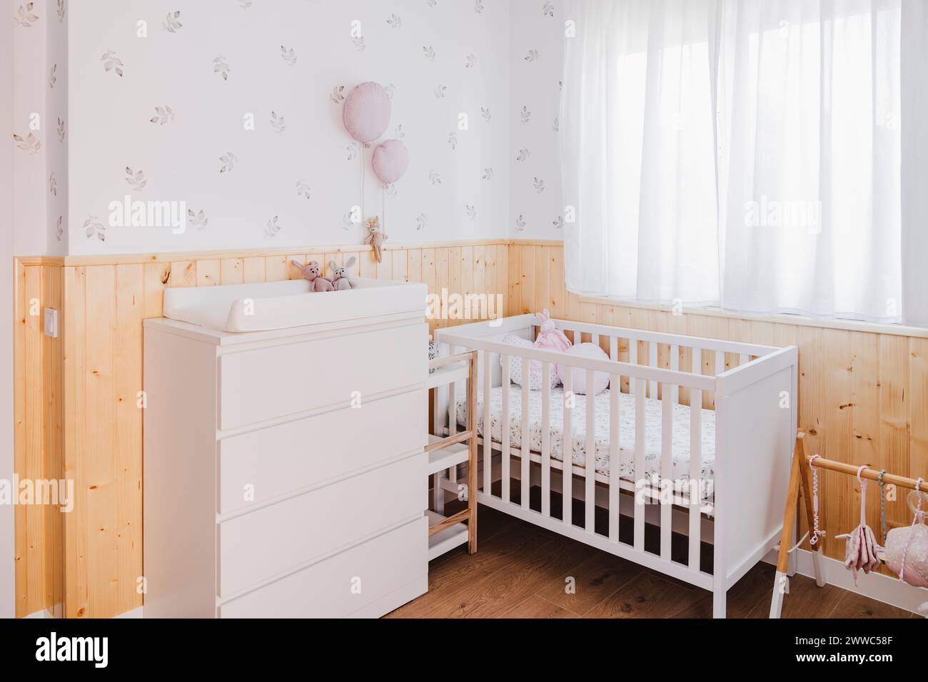 Decorated nursery room with crib and dresser near window Stock Photo ...