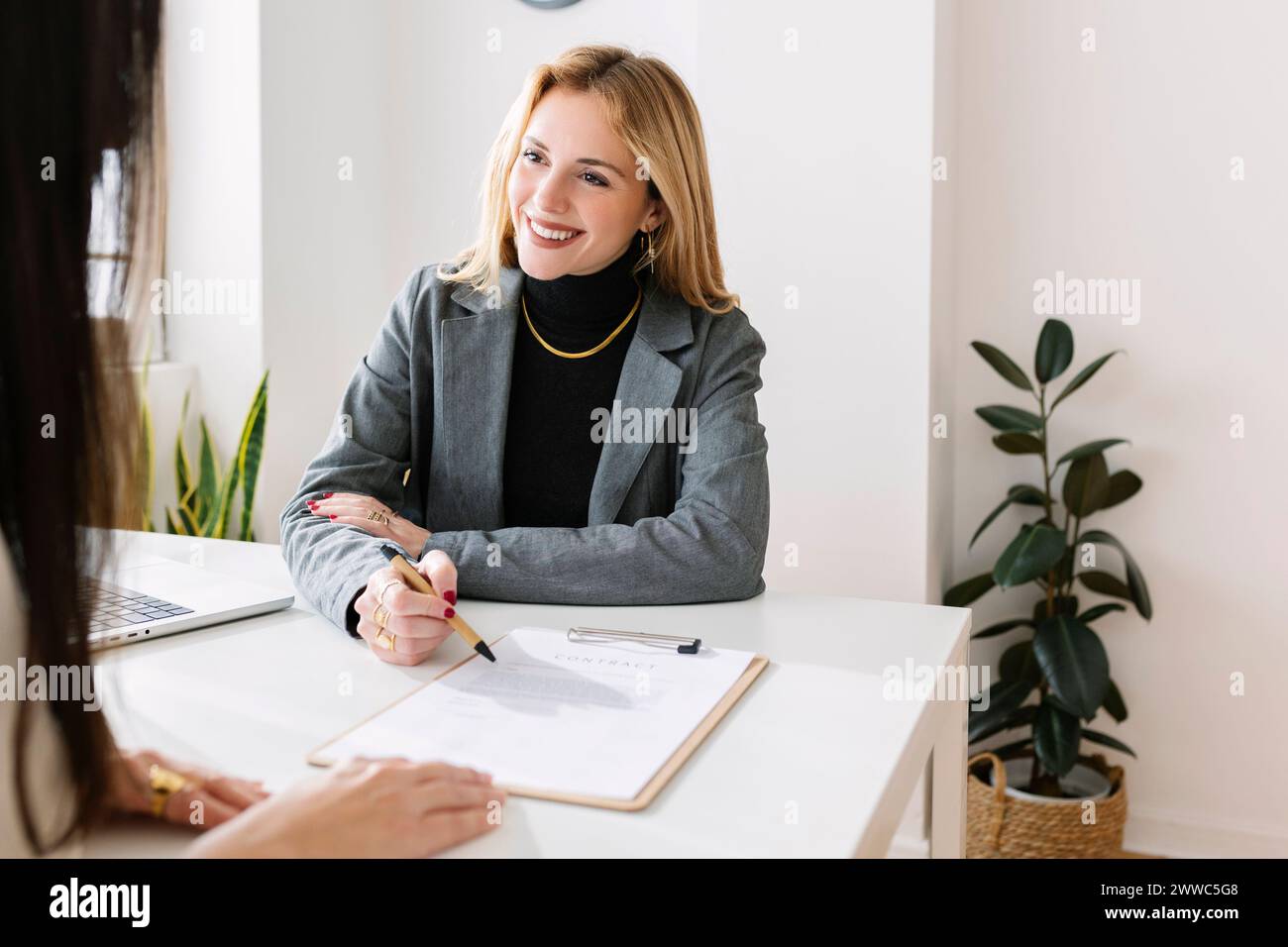 Happy businesswoman explaining contract to colleague at desk Stock ...