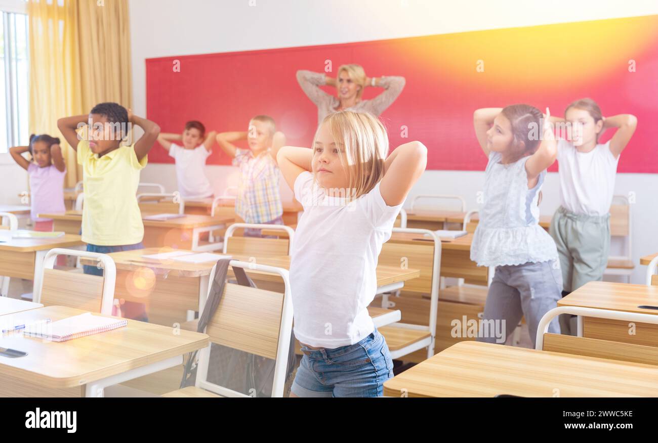 Preteen pupils doing warm-up in class with teacher at lesson Stock ...