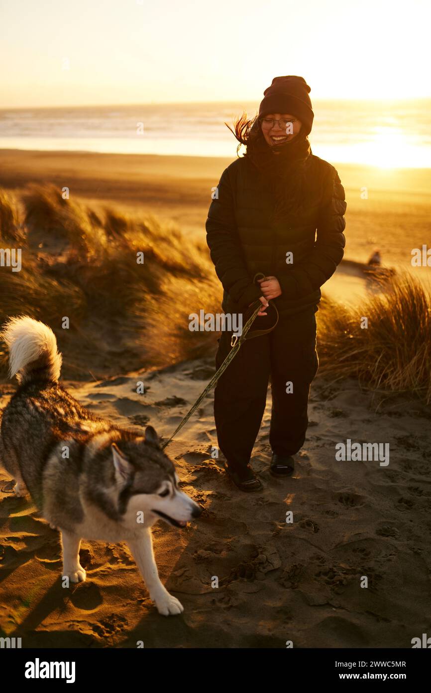 Happy young woman walking Husky dog at beach Stock Photo - Alamy