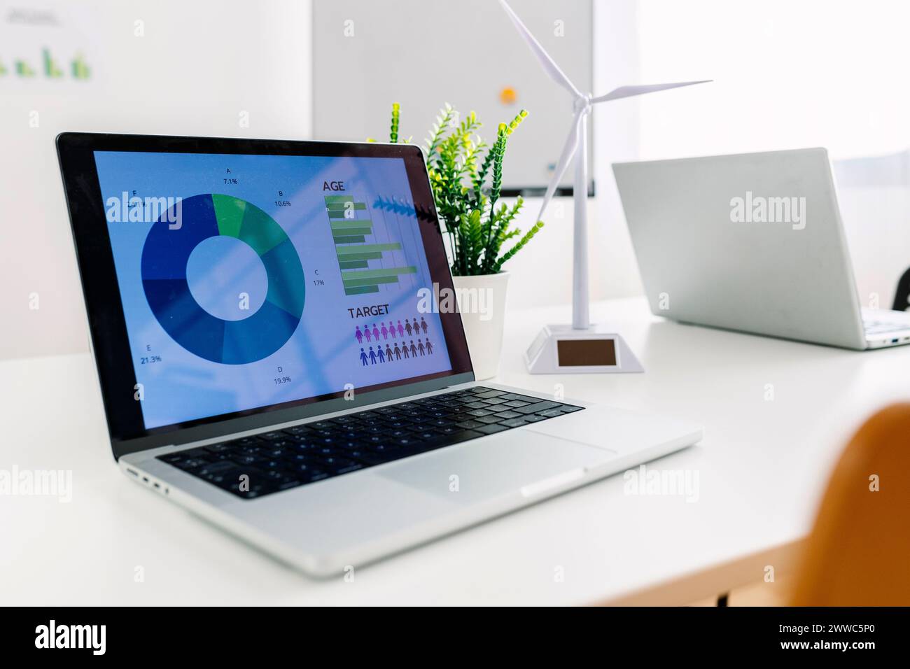 Laptop with charts and graphs on screen near wind turbine model at ...