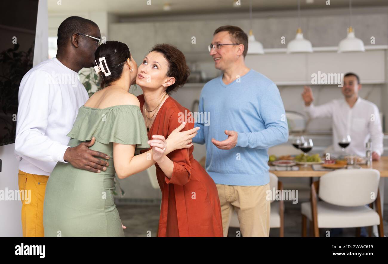 Smiling woman hostess hugging and kissing guest at dinner party Stock ...