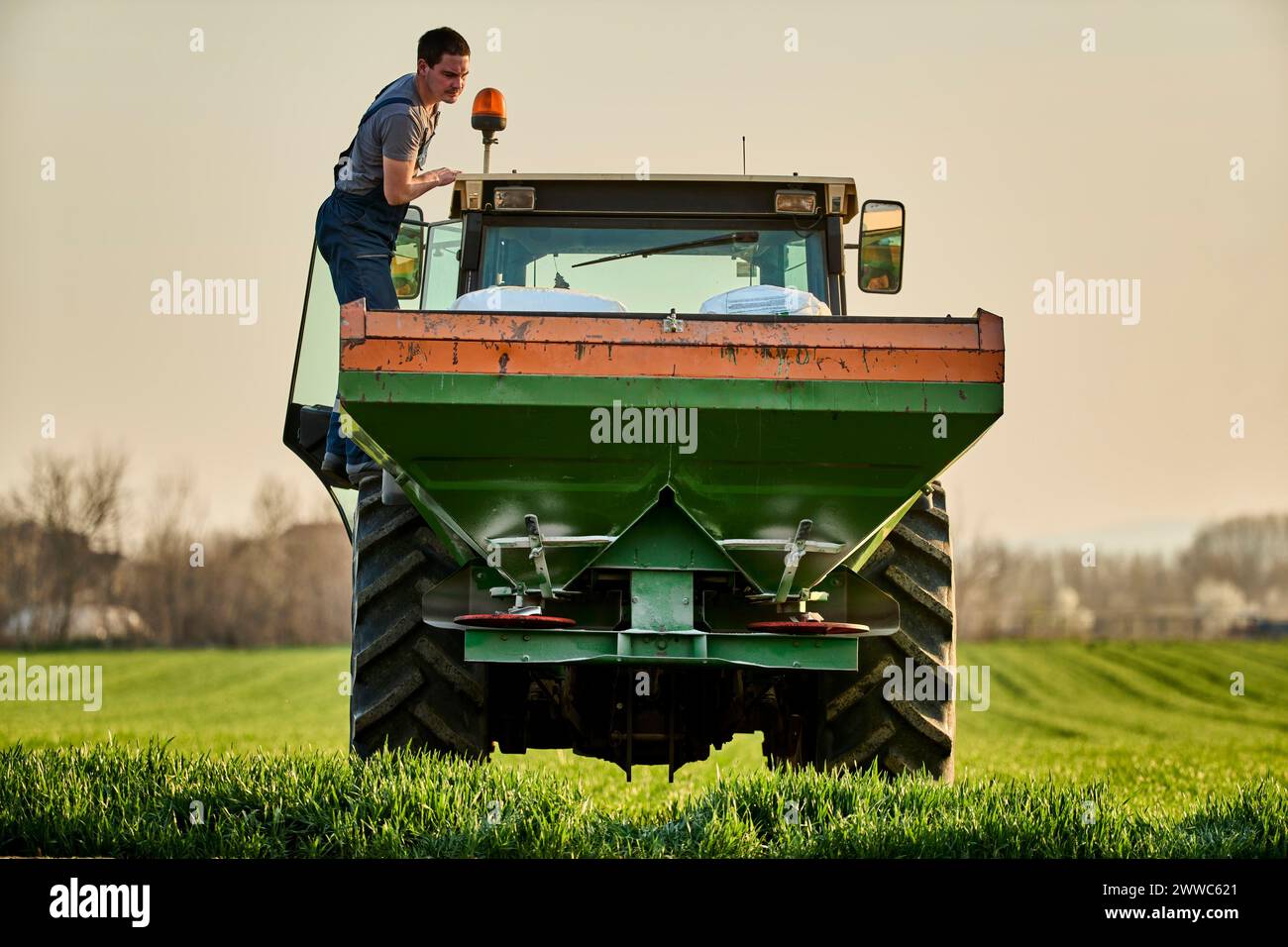 Farmer examining tractor on field Stock Photo - Alamy