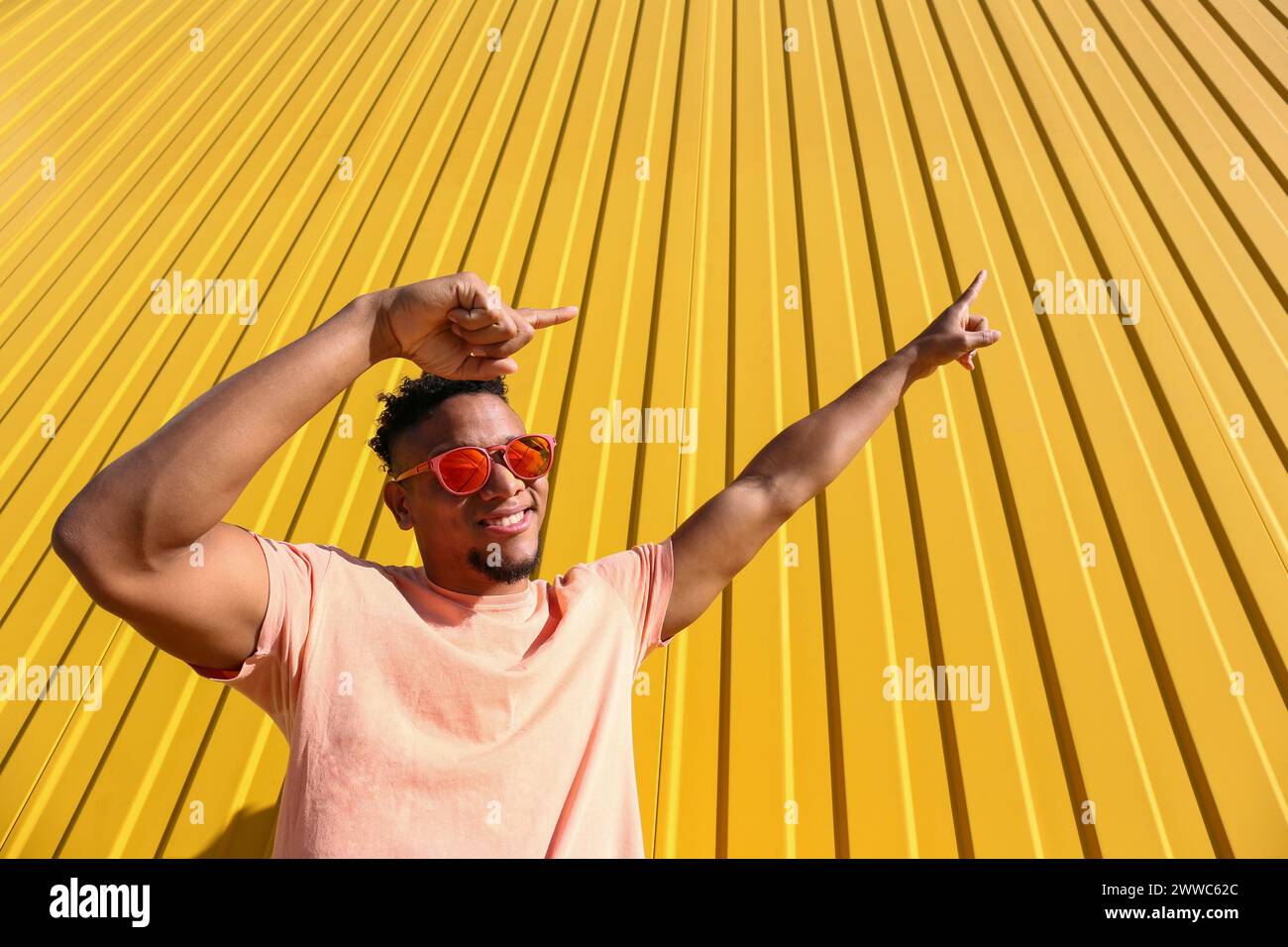 Happy young man dabbing in front of yellow wall Stock Photo - Alamy