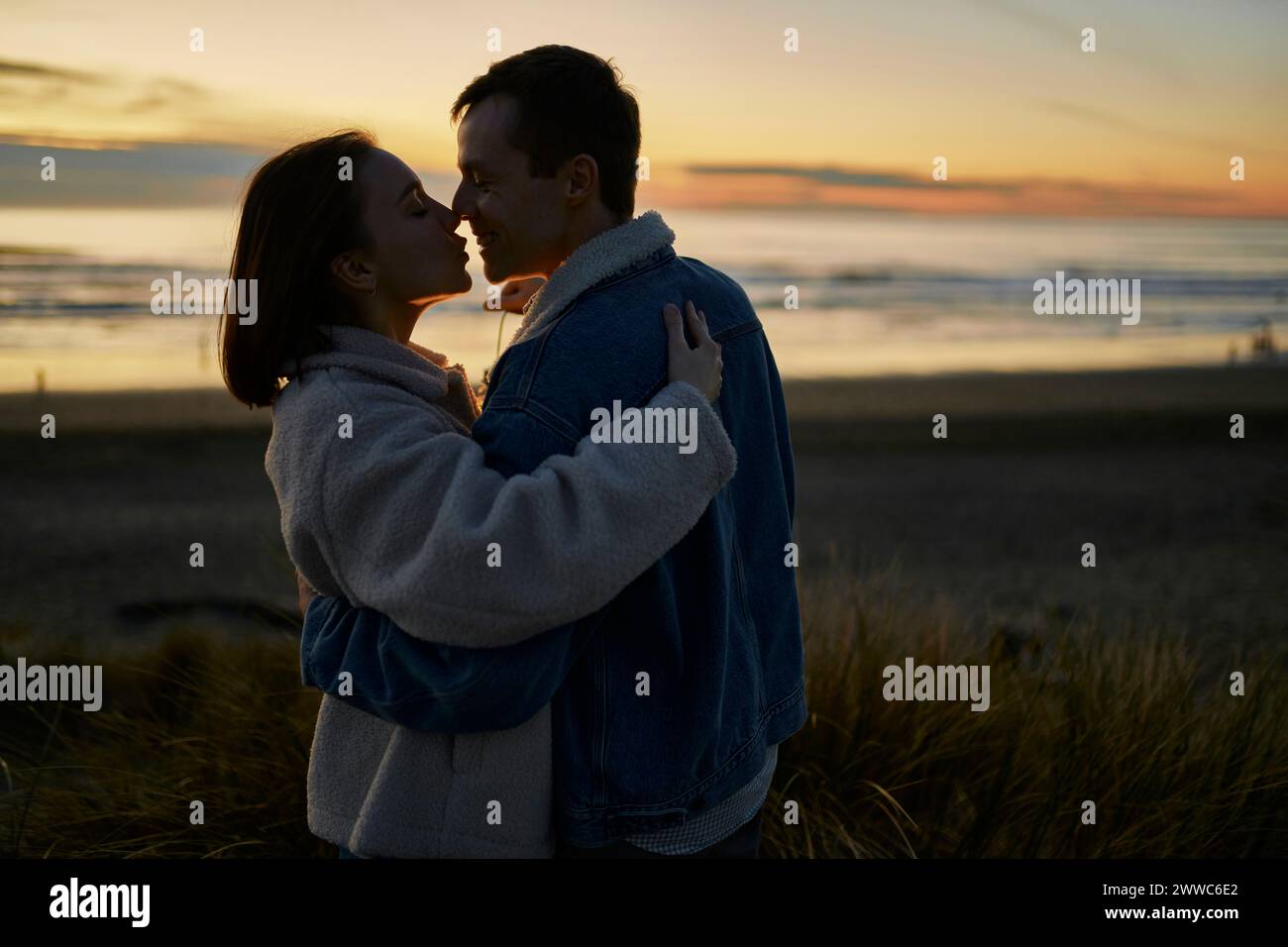 Affectionate girlfriend and boyfriend embracing on beach at sunset ...