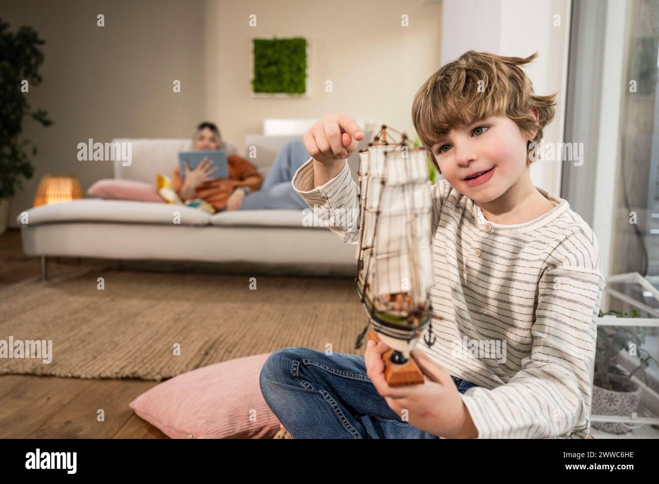 Boy sitting with model ship at home Stock Photo - Alamy