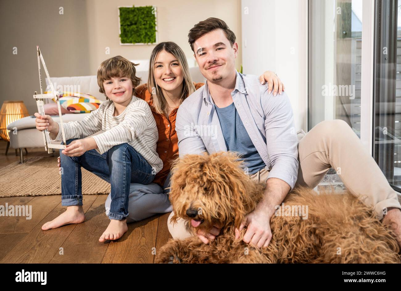 Happy family with model house and dog sitting in living room Stock ...