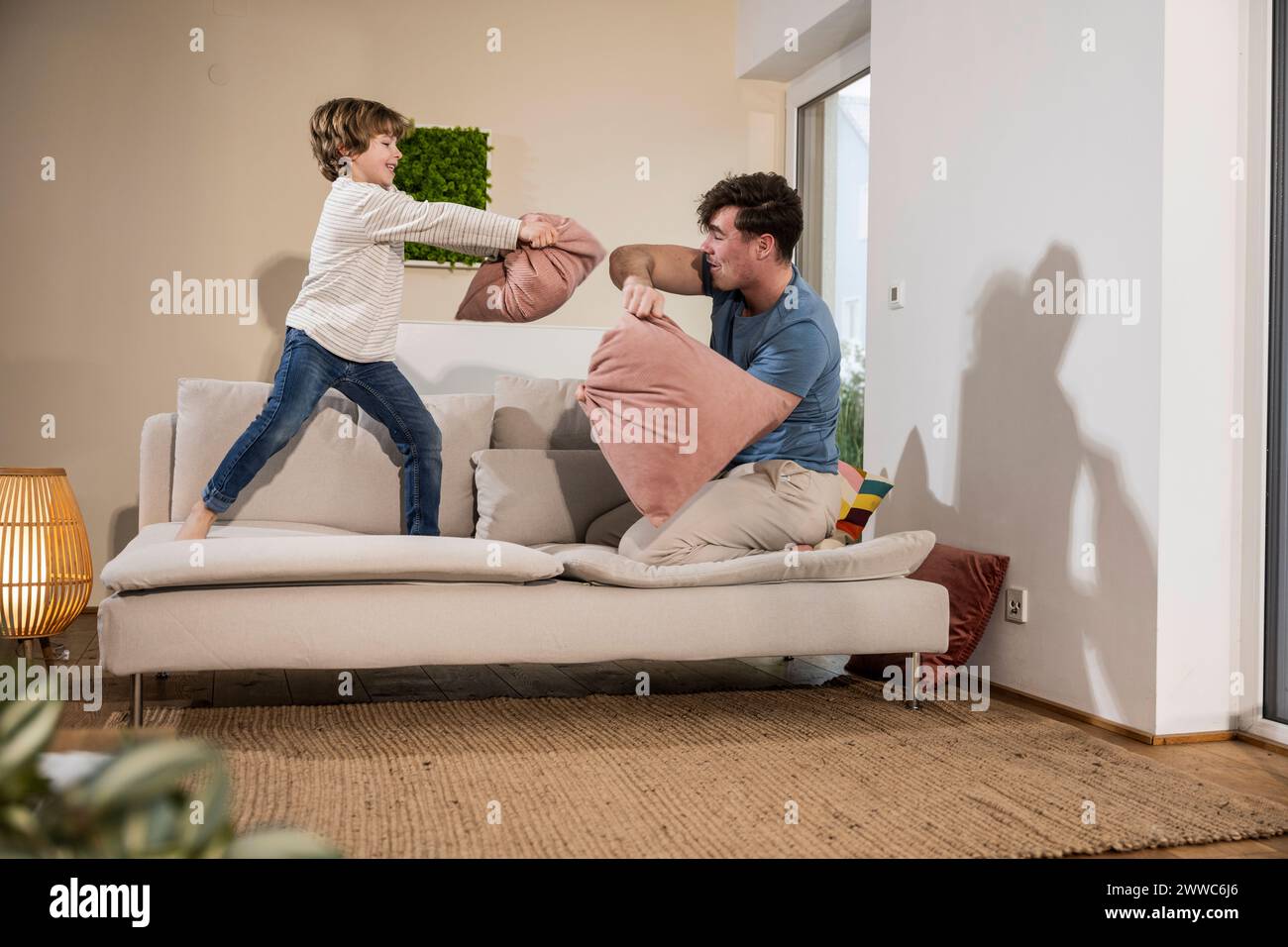 Happy father playing pillow fight with son at home Stock Photo - Alamy