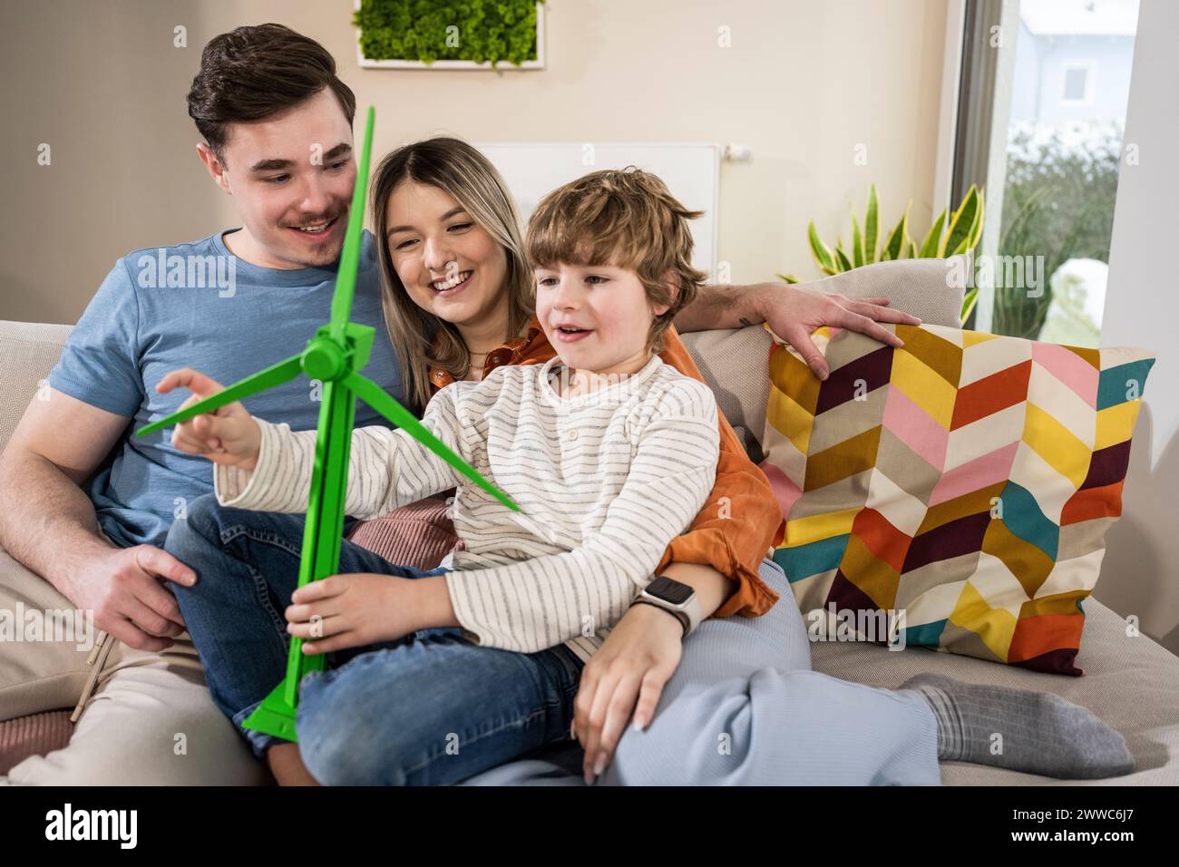 Happy family sitting with wind turbine model at home Stock Photo - Alamy
