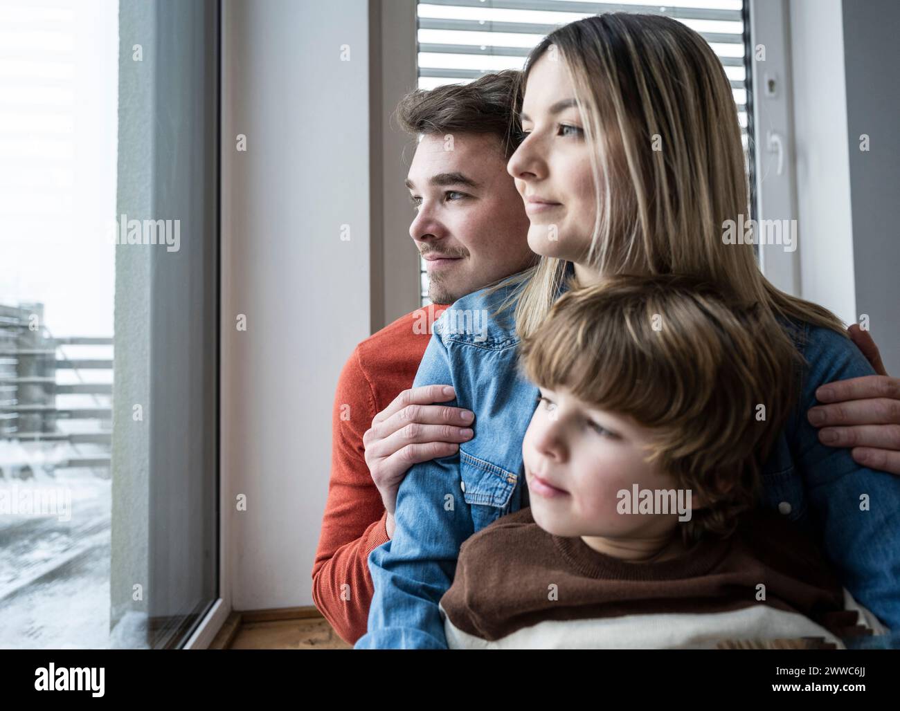 Smiling father and mother with son looking through window at home Stock ...