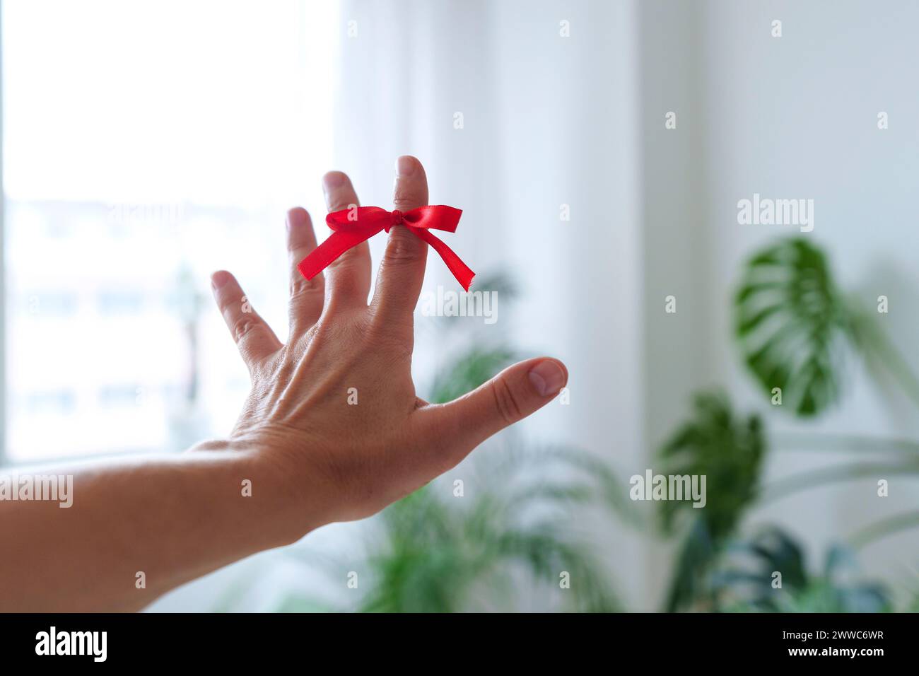 Hand of woman with reminder knot on index finger at home Stock Photo ...