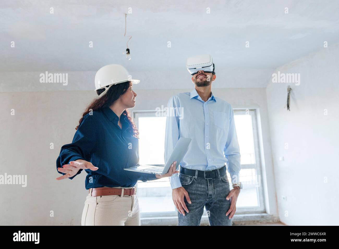 Real estate agent explaining about new renovation ideas to man wearing ...