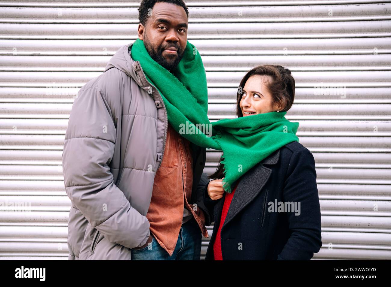 Couple wearing same scarf and standing in front of shutter Stock Photo ...