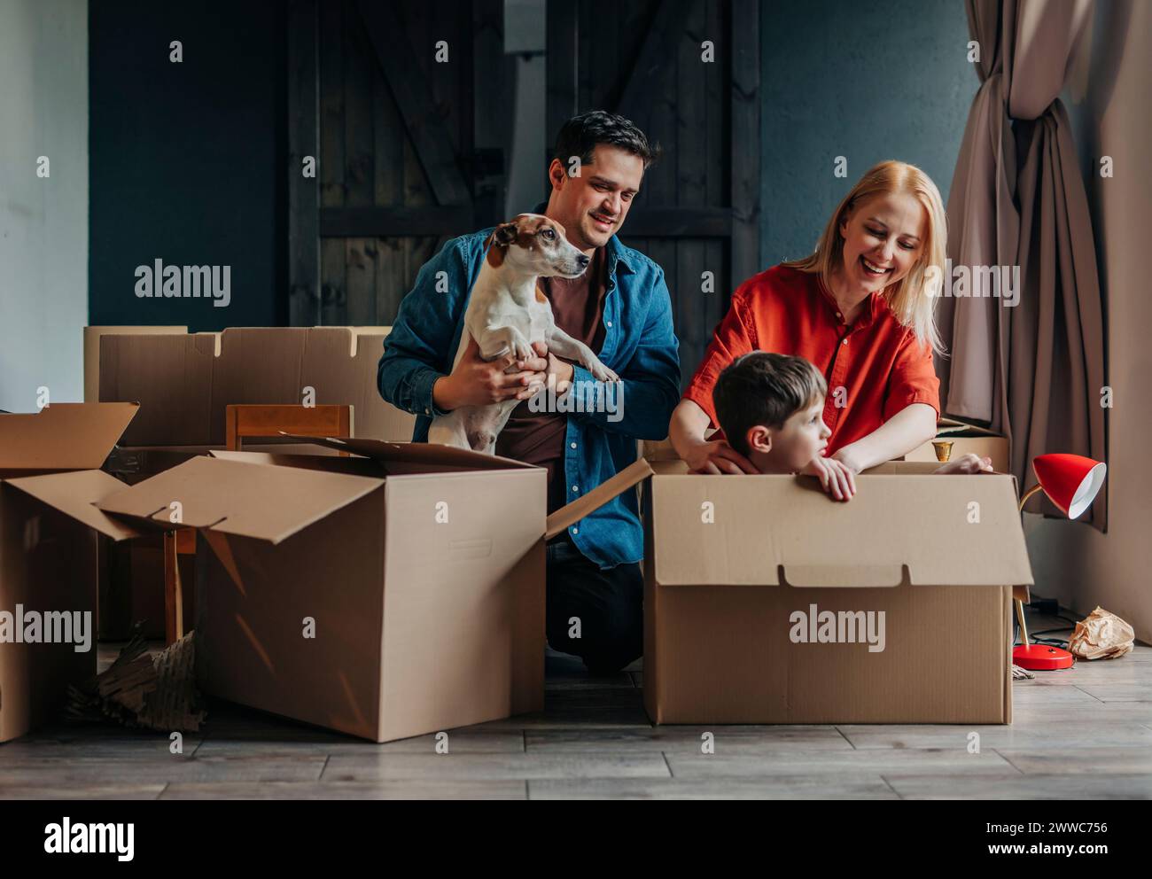 Happy parents with son sitting in box at home Stock Photo - Alamy