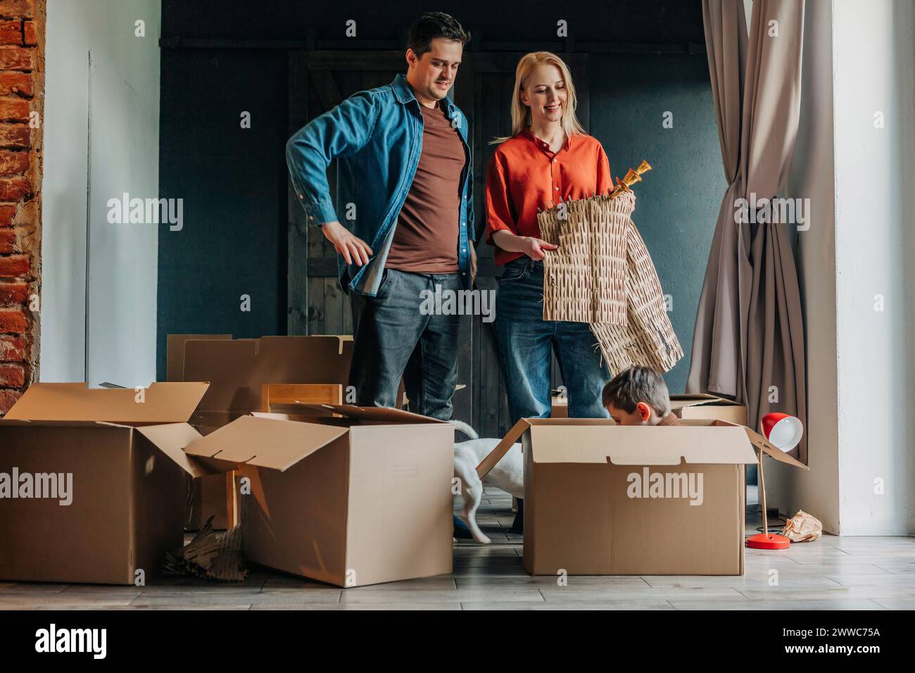 Happy family packing cardboard boxes for moving Stock Photo - Alamy