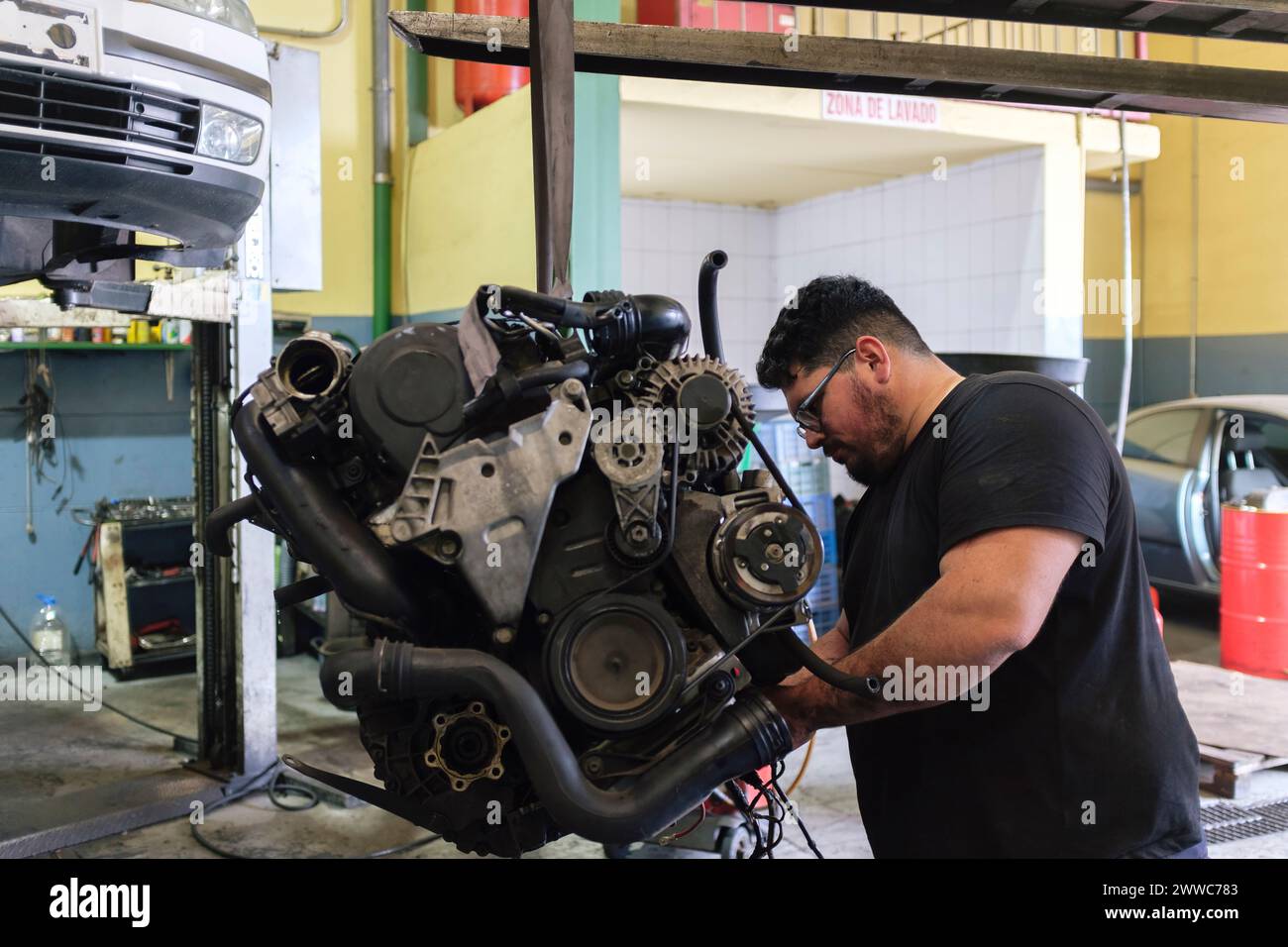 Mechanic disassembling vehicle engine at workshop Stock Photo - Alamy