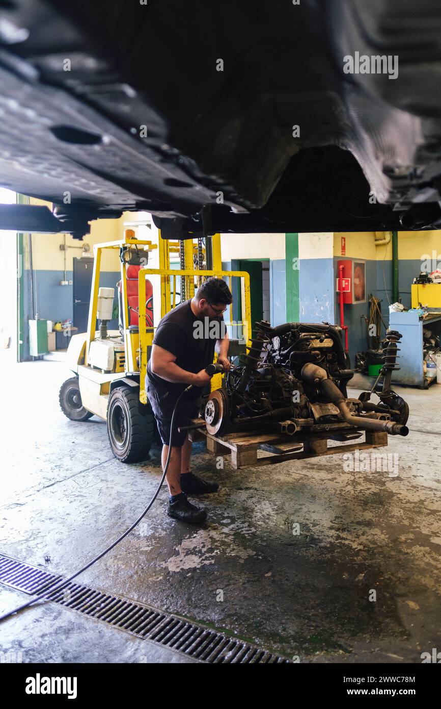Mechanic dismantling engine using impact wrench at workshop Stock Photo ...