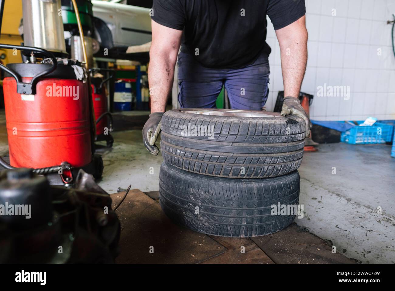 Mechanic placing vehicle tires on floor at workshop Stock Photo - Alamy
