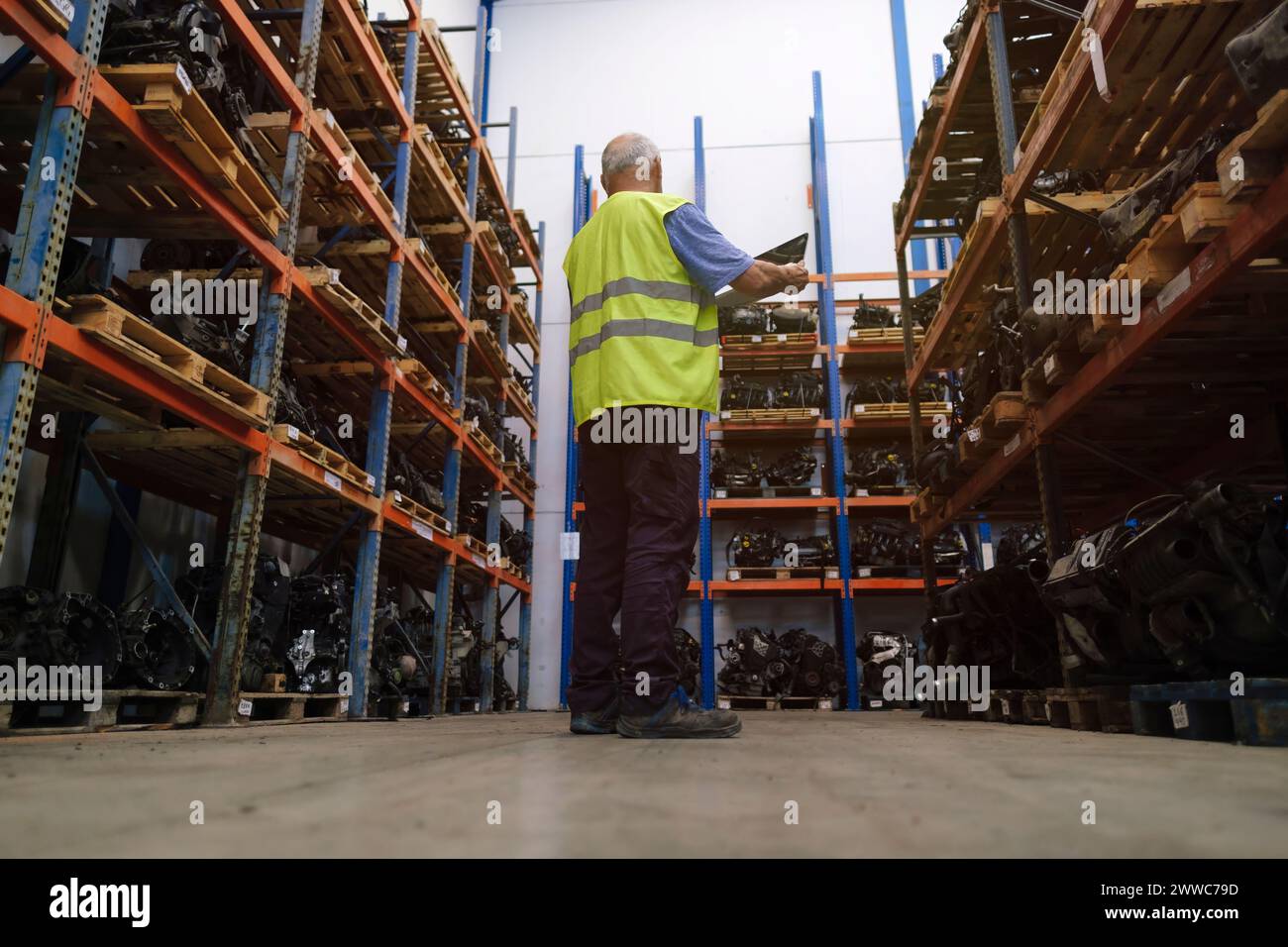 Senior auto mechanic taking standing amidst shelves at warehouse Stock ...
