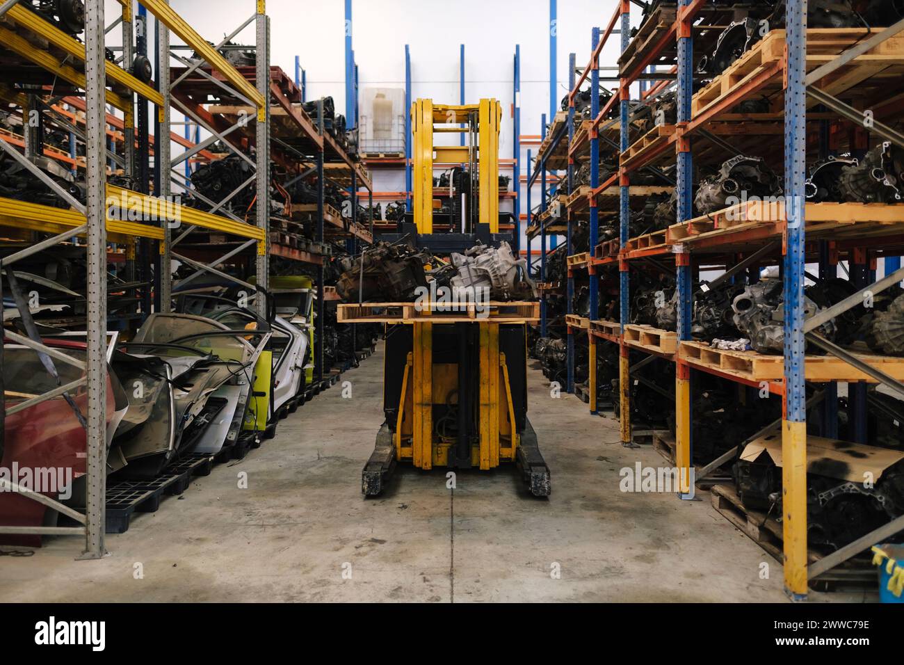 Forklift amidst shelves of vehicle parts at warehouse Stock Photo - Alamy