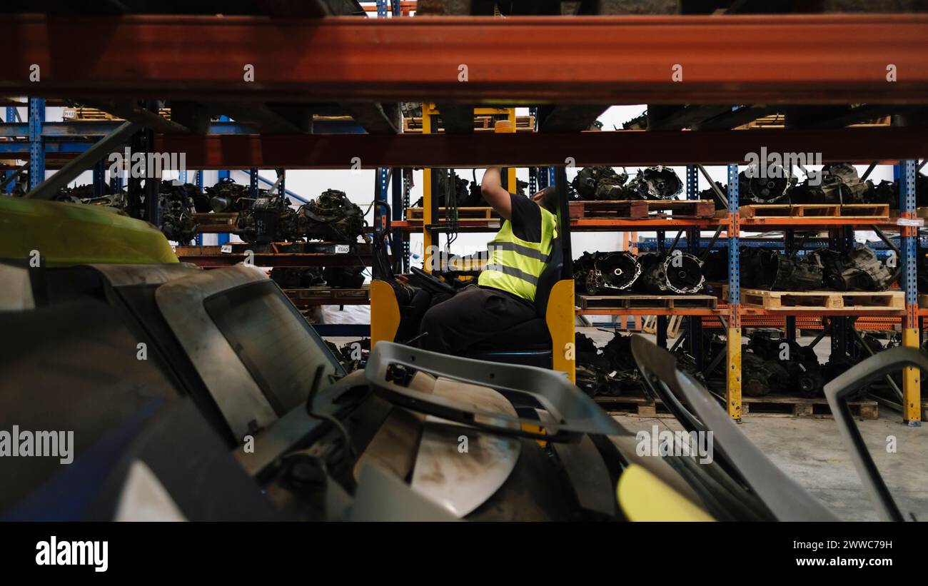 Mechanic sitting in forklift near shelves at warehouse Stock Photo - Alamy
