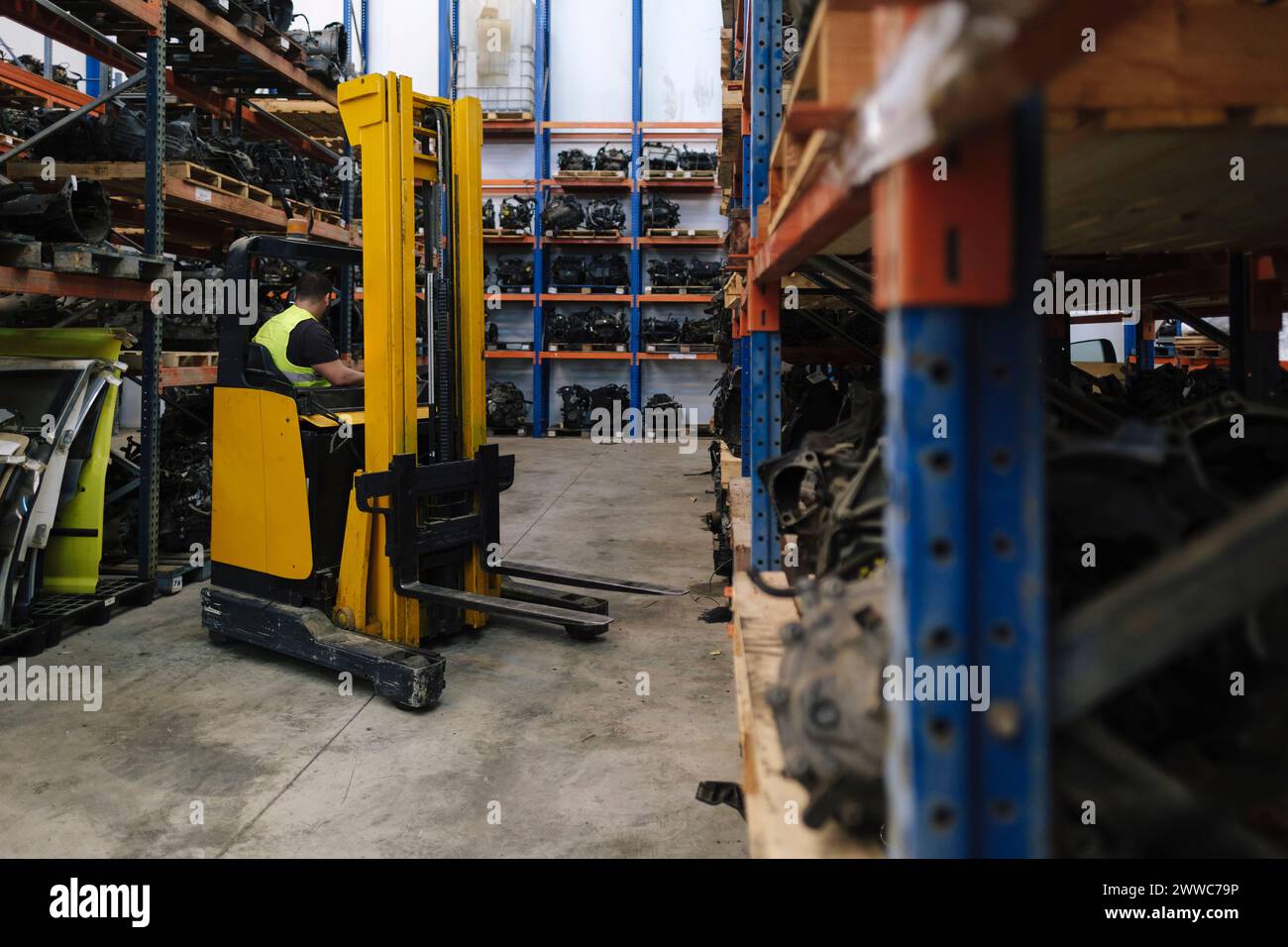 Mechanic operating forklift near shelves at warehouse Stock Photo - Alamy