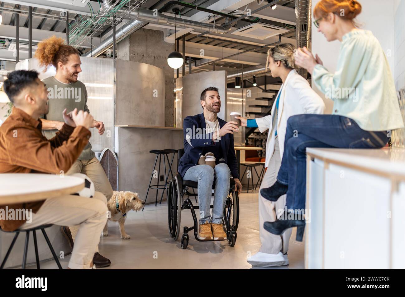 Businessman in wheelchair giving coffee to colleagues at office cafe ...