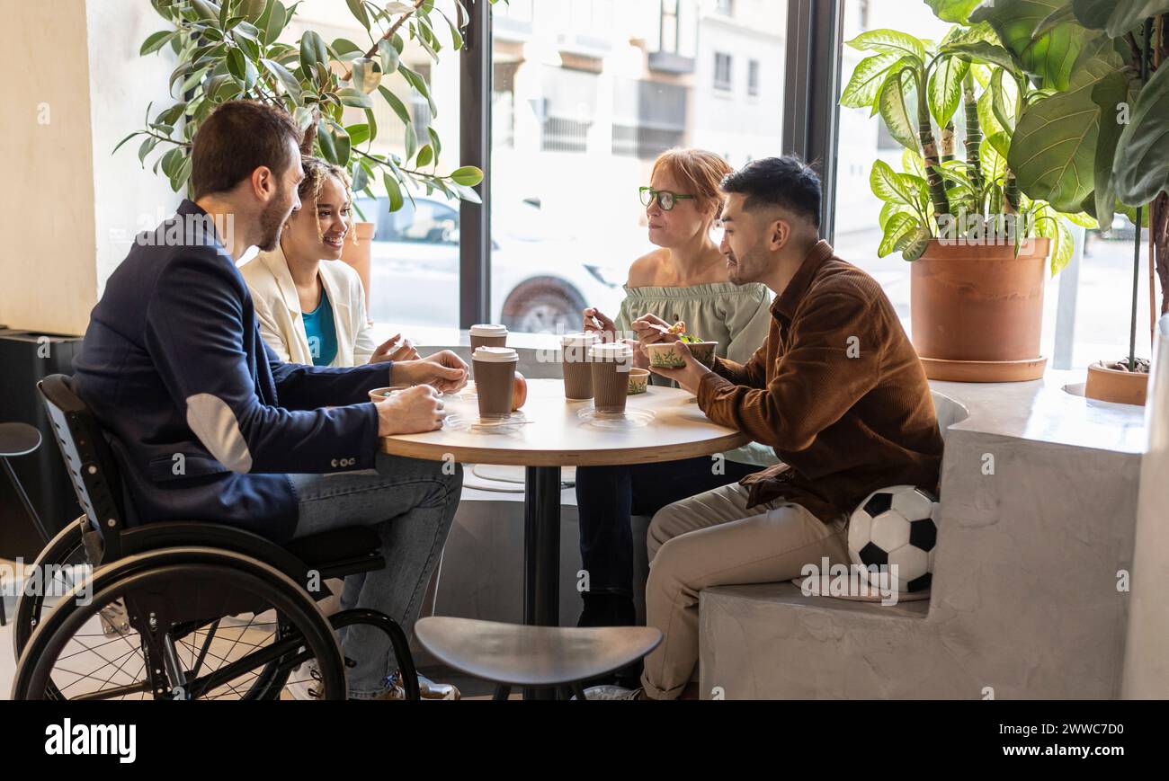 Diverse business colleagues having food at lunch break in office cafe ...