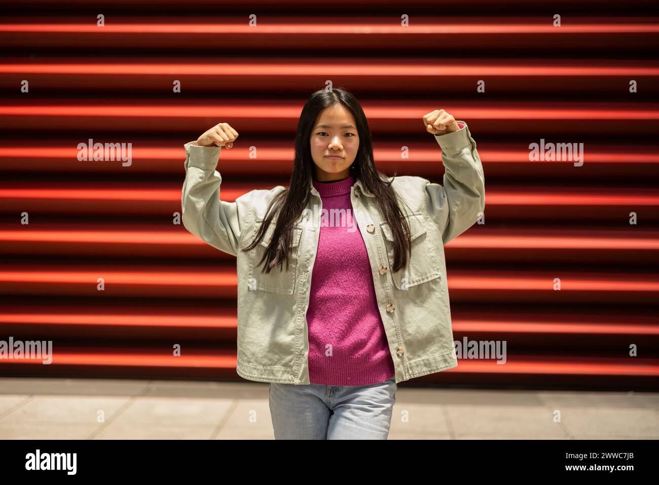 Young woman flexing muscles in front of shutter Stock Photo - Alamy