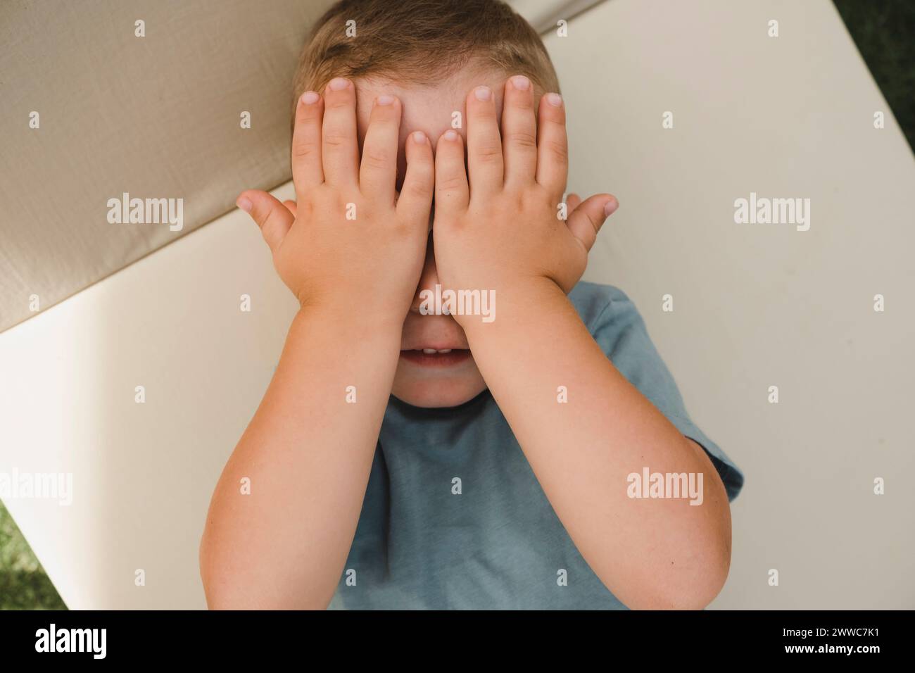 Shy boy covering eyes with hands Stock Photo - Alamy