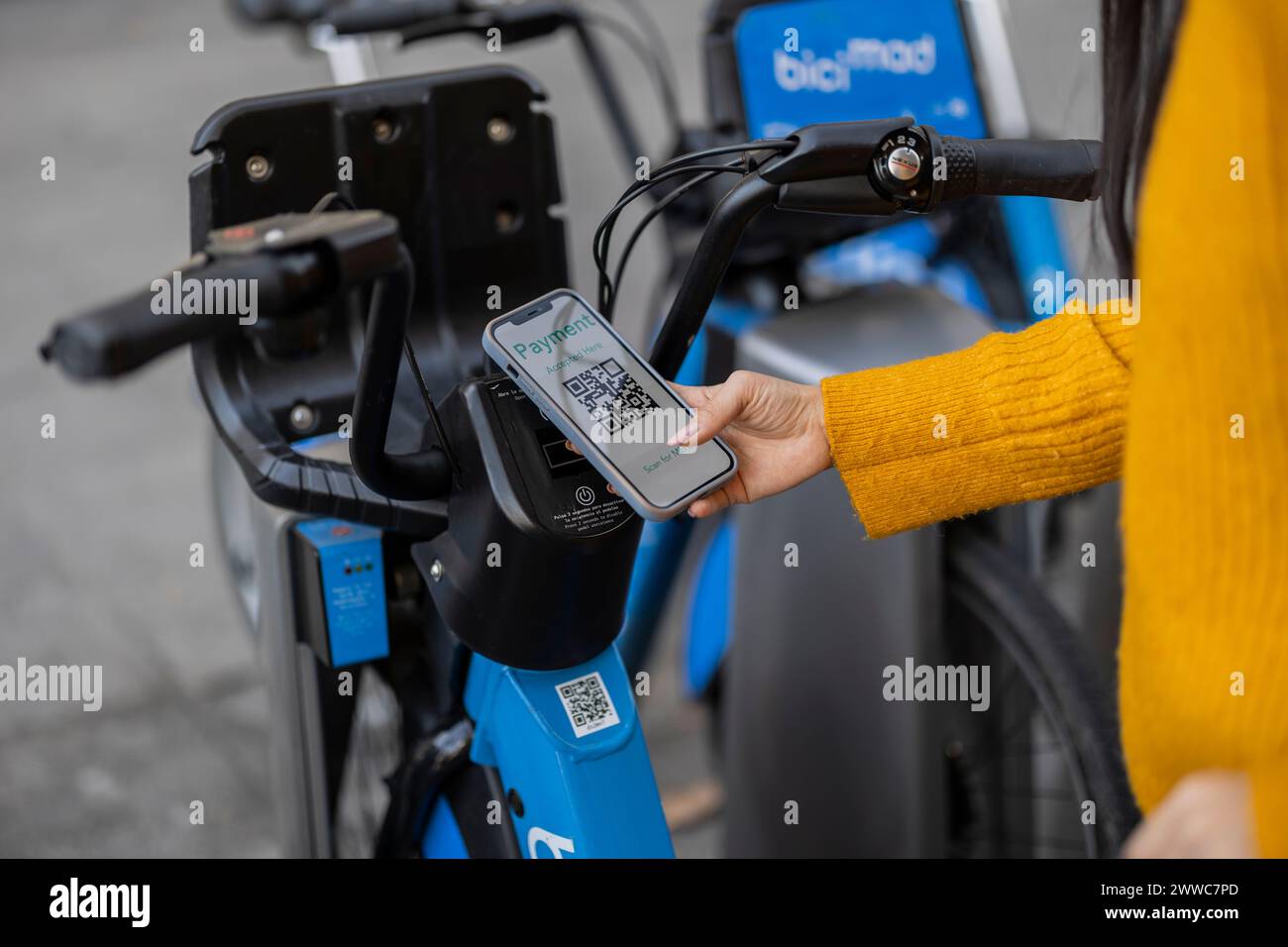 Woman scanning QR code through smart phone and renting electric bicycle ...