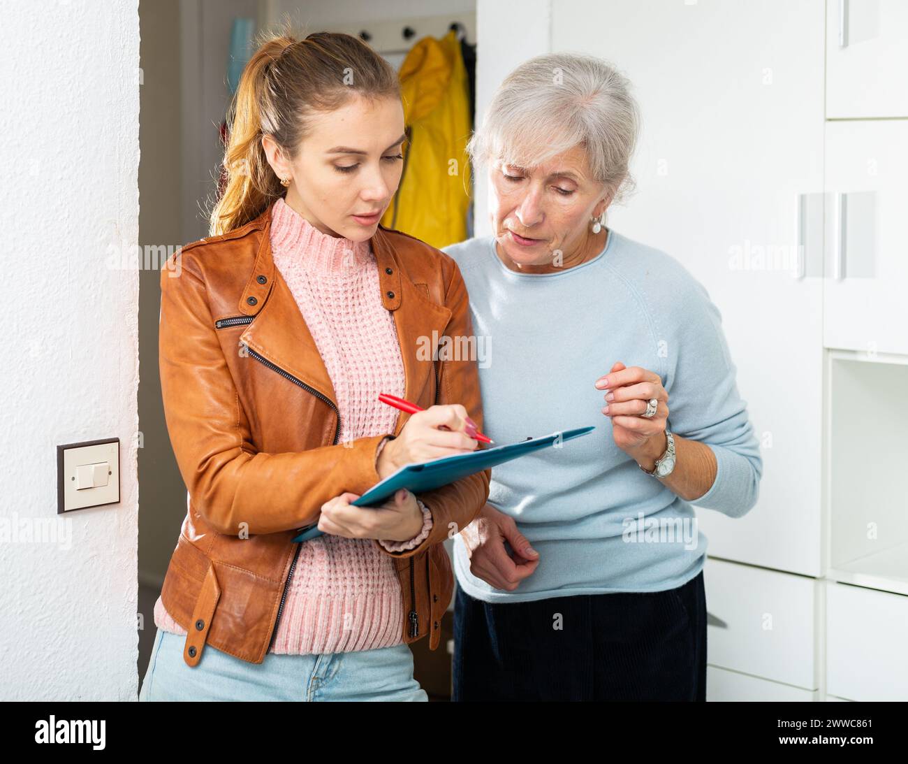 Senior and younger women filling rent contract Stock Photo - Alamy