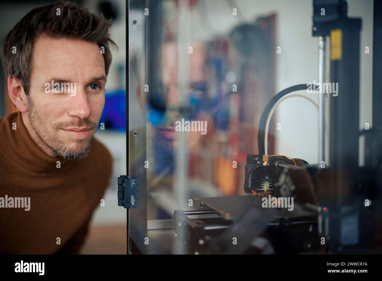 Engineer looking at 3d printer inside glass cabinet at workshop Stock ...