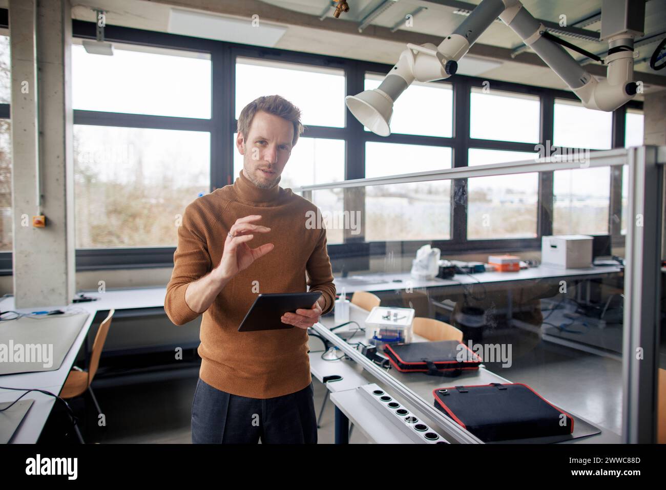Engineer holding tablet PC and gesturing at workshop Stock Photo - Alamy