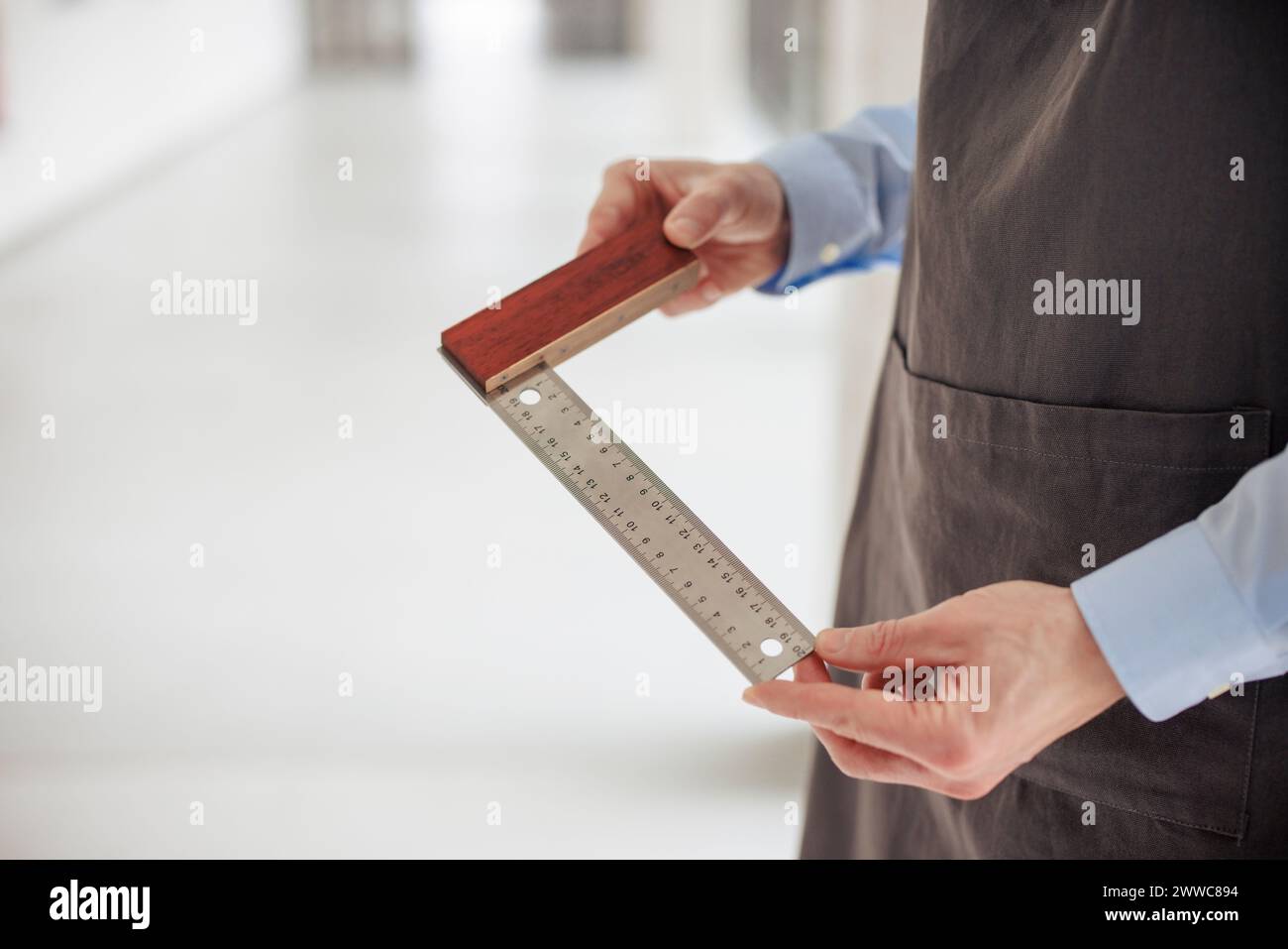 Engineer wearing apron and holding measuring ruler at workshop Stock ...