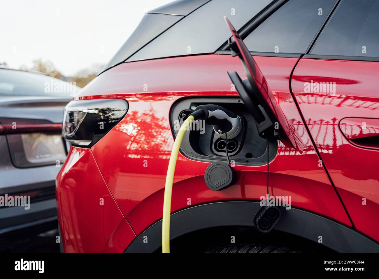 Electric car charging through plug on street Stock Photo - Alamy