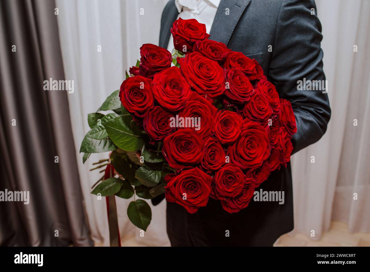 Teenage boy holding bouquet of red roses at home Stock Photo - Alamy