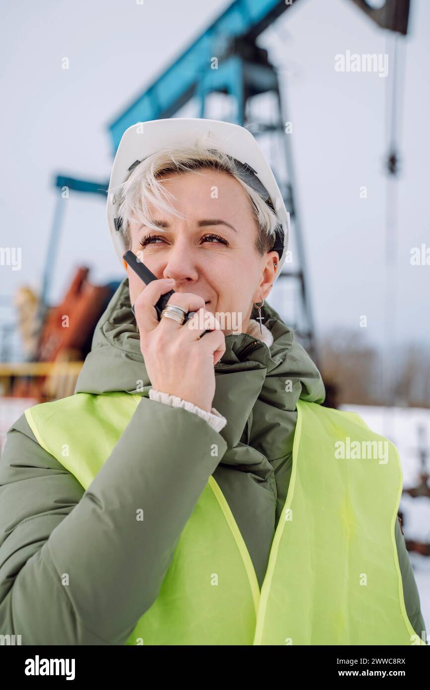 Engineer talking on walkie-talkie at oil production field in winter ...