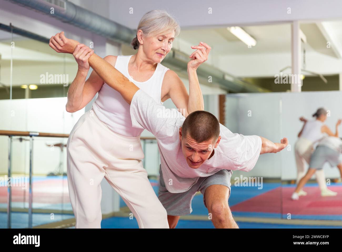 Elderly woman performing elbow strike and wristlock to man in self ...