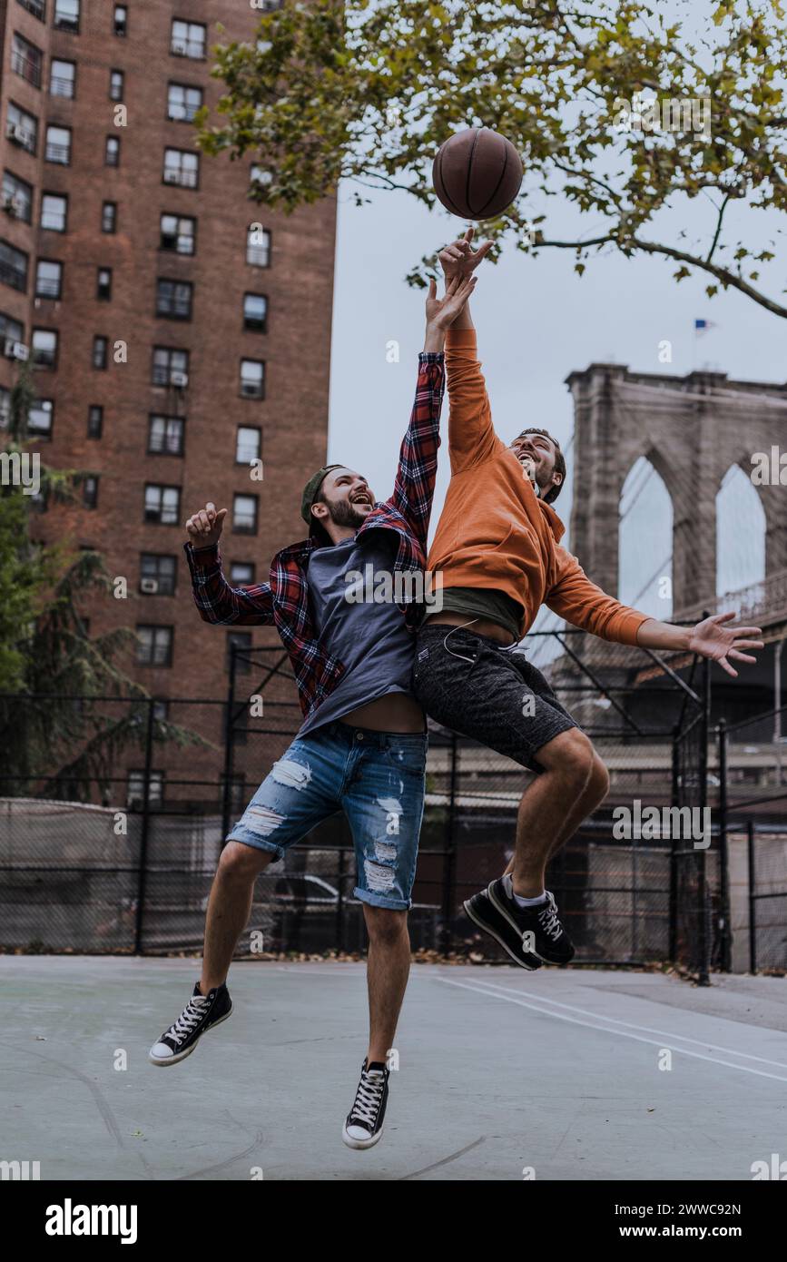 Happy friends slam dunking basketball at court Stock Photo - Alamy