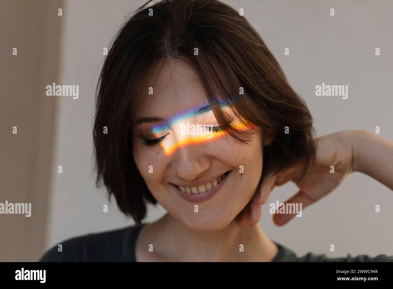Smiling young woman with multi-colored light on face Stock Photo - Alamy