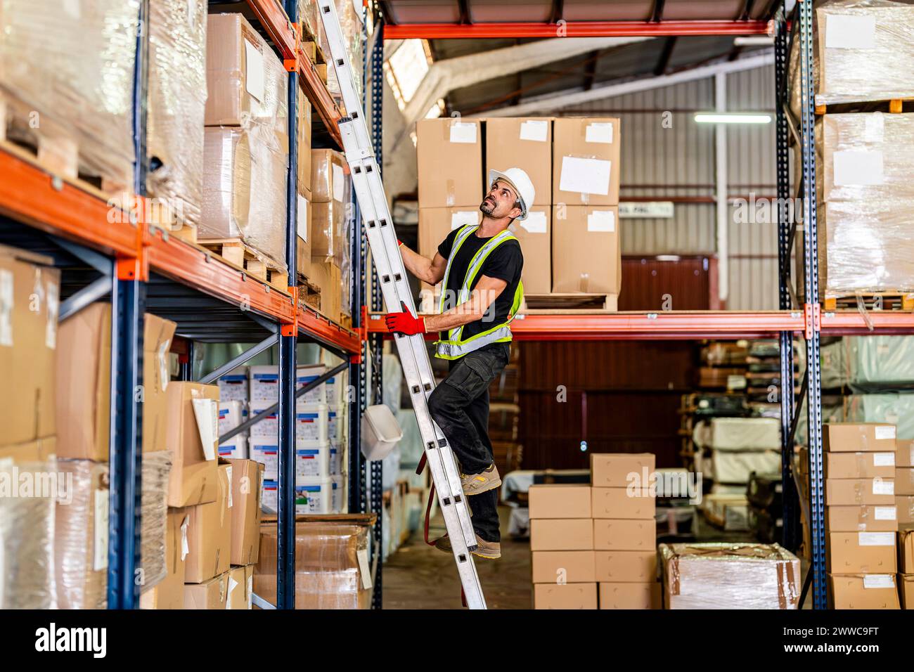 Worker climbing on ladder and reaching for boxes Stock Photo - Alamy