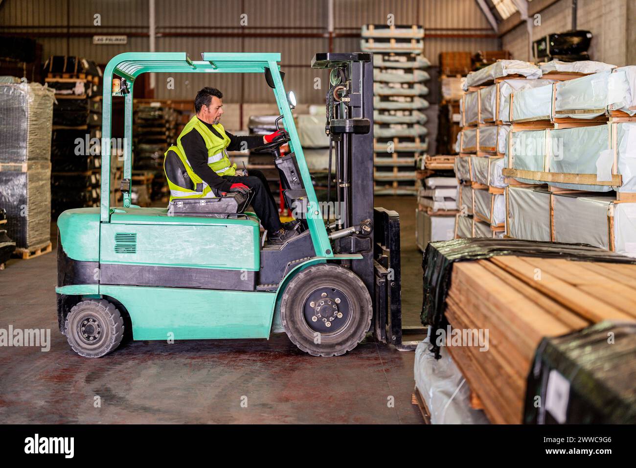 Worker operating forklift at warehouse Stock Photo - Alamy
