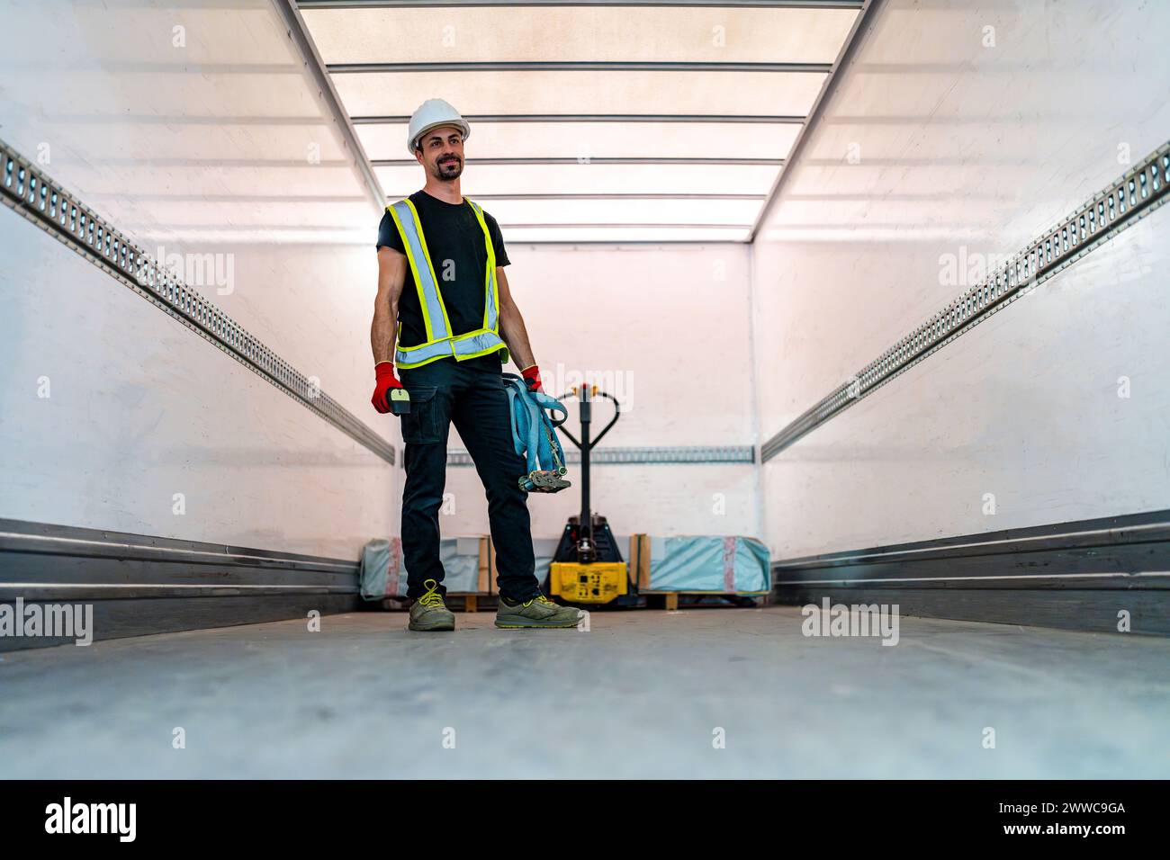 Worker standing near pallet jack inside cargo container Stock Photo - Alamy