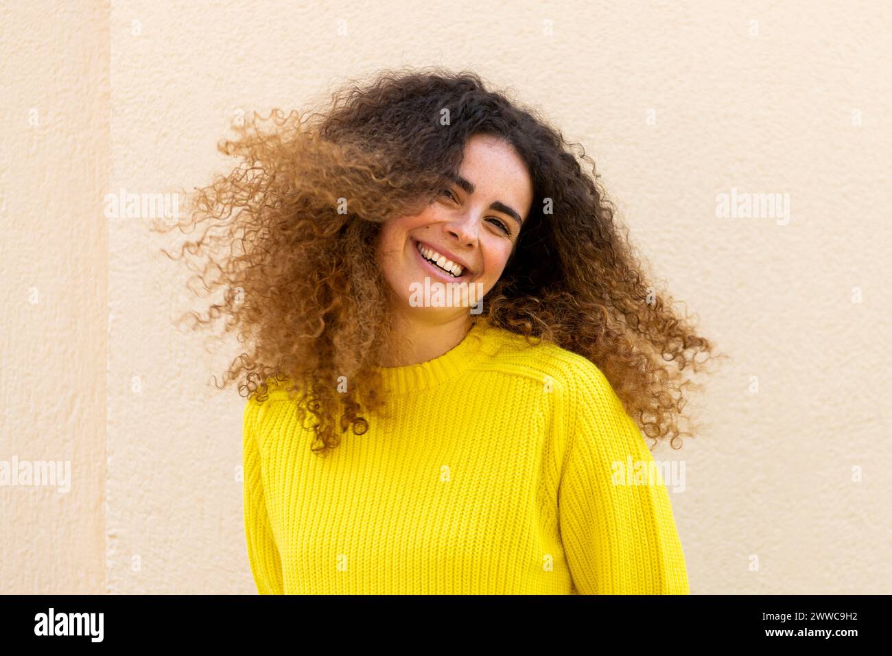 Happy woman tossing hair in front of wall Stock Photo - Alamy