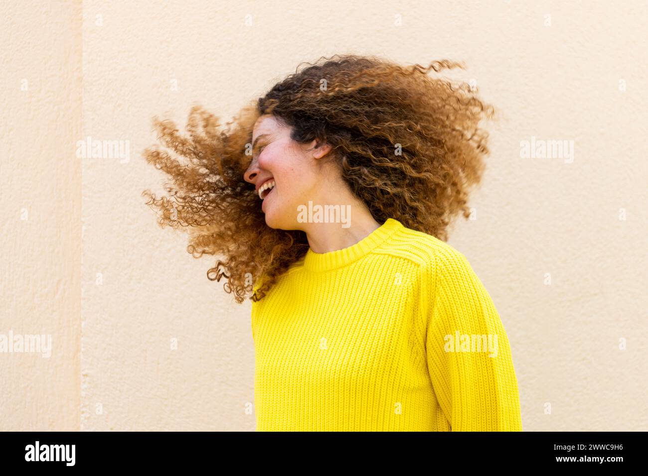 Cheerful woman tossing hair in front of wall Stock Photo - Alamy