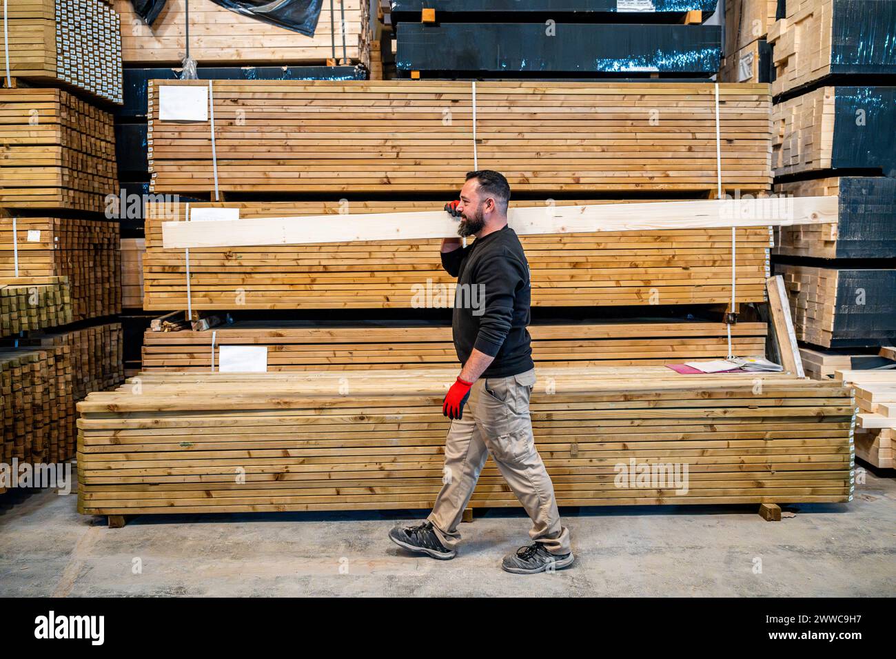 Worker carrying wooden plank at warehouse Stock Photo - Alamy