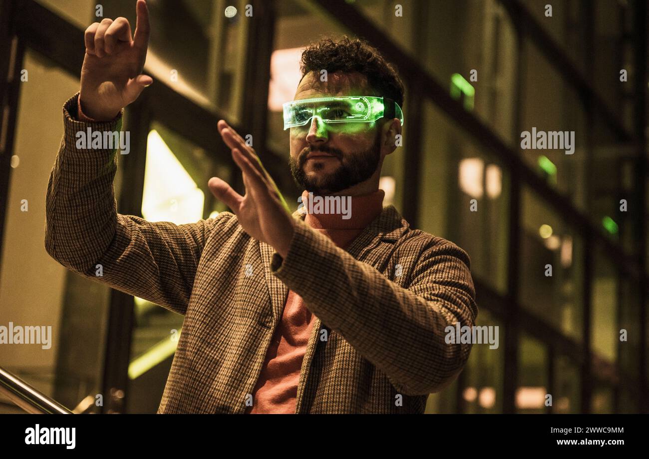 Man wearing smart glasses and gesturing near building at night Stock ...